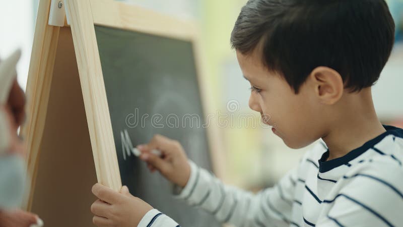 Adorable Hispanic Boy Preschool Student Writing on Blackboard at ...