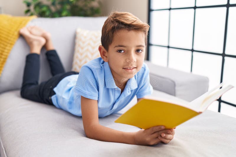 Adorable Hispanic Boy Reading Book Lying on Sofa at Home Stock Image ...