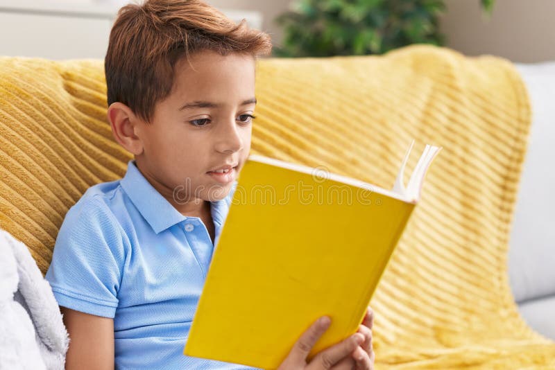 Adorable Hispanic Boy Reading Book Sitting on Sofa at Home Stock Photo ...