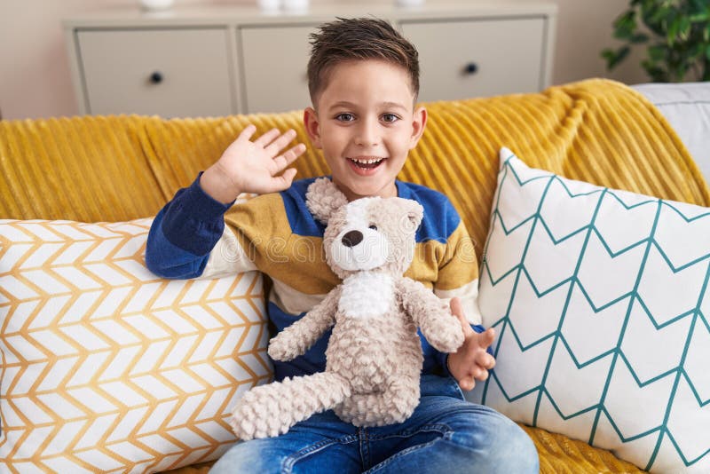 Adorable Hispanic Boy Saying Hello with Hand Sitting on Sofa at Home ...