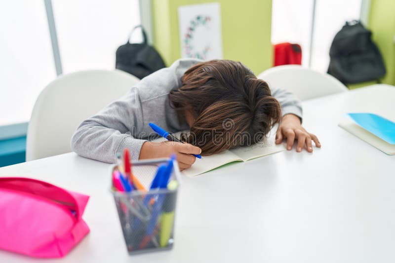 Adorable Hispanic Boy Student with Head on Table Stressed at Classroom ...