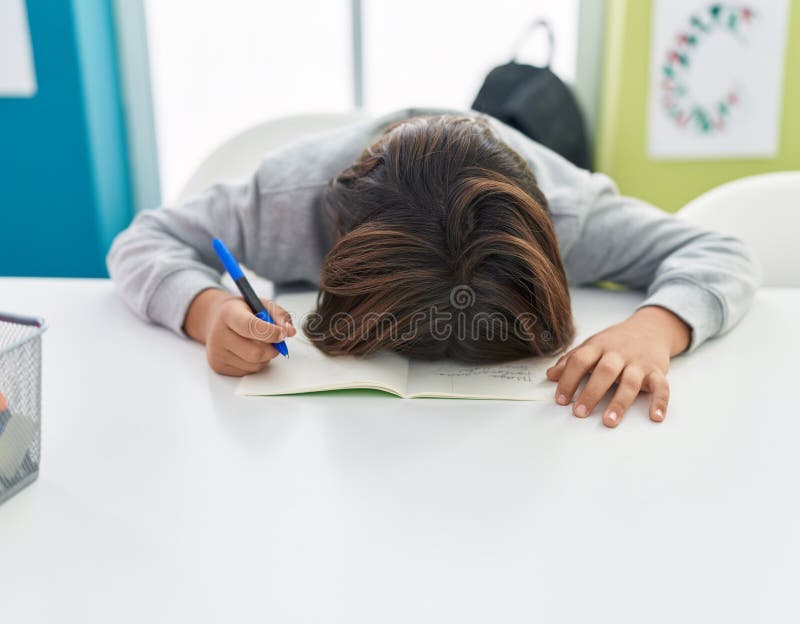 Adorable Hispanic Boy Student with Head on Table Stressed at Classroom ...