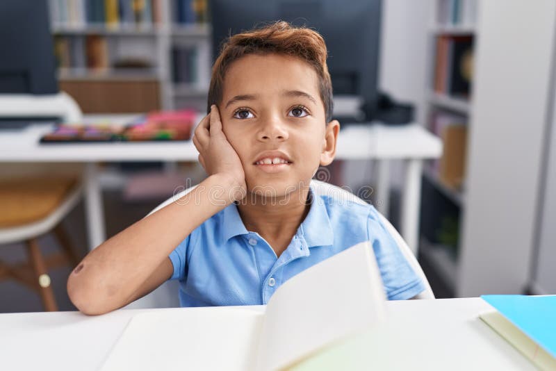 Adorable Hispanic Boy Student Reading Book Thinking at Classroom Stock ...