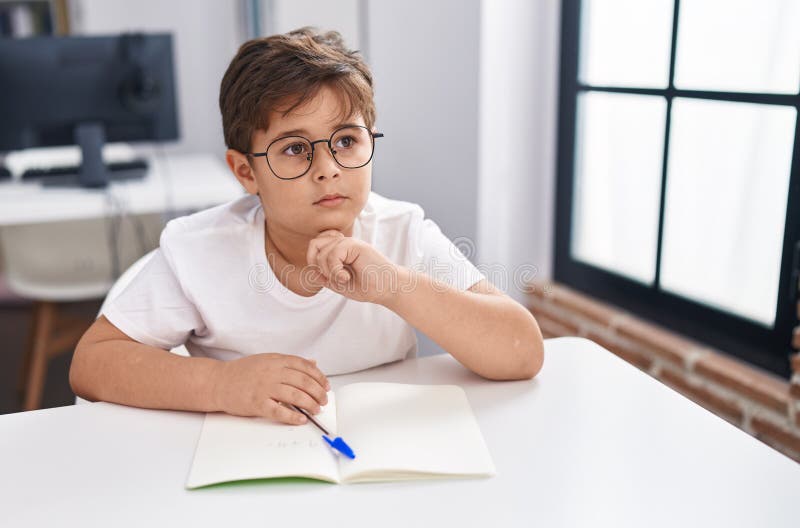 Adorable Hispanic Boy Student Reading Book Thinking at Classroom Stock ...