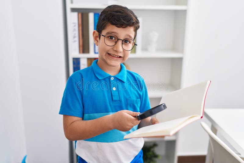 Adorable Hispanic Boy Student Reading Book Using Magnifying Glass at ...