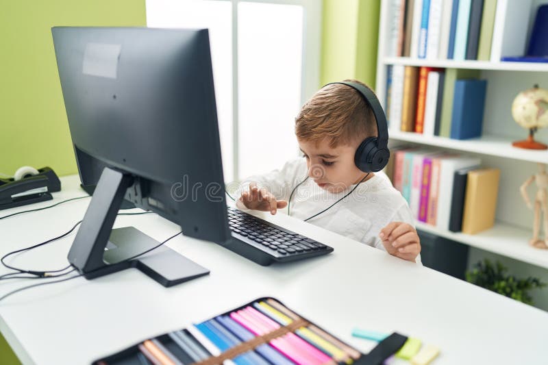 Adorable Hispanic Boy Student Using Computer and Headphones Sitting on ...
