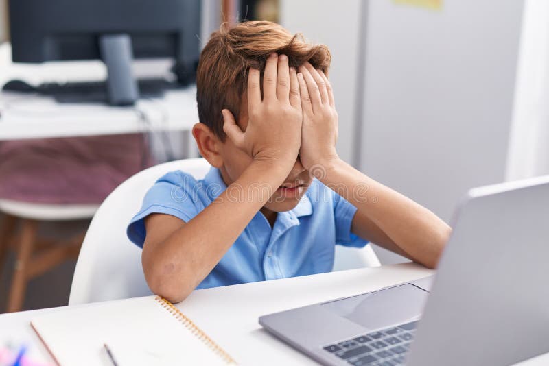 Adorable Hispanic Boy Student Using Computer with Stressed Expression at Classroom Stock Image ...