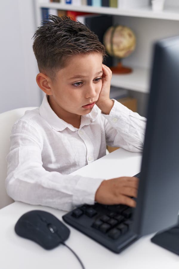 Adorable Hispanic Boy Student Using Computer with Tired Expression at ...