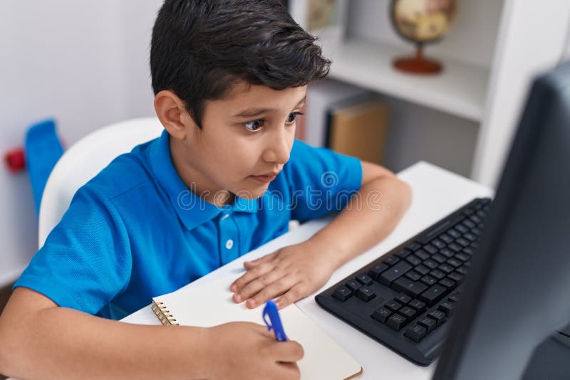 Adorable Hispanic Boy Student Using Computer Writing on Notebook at ...
