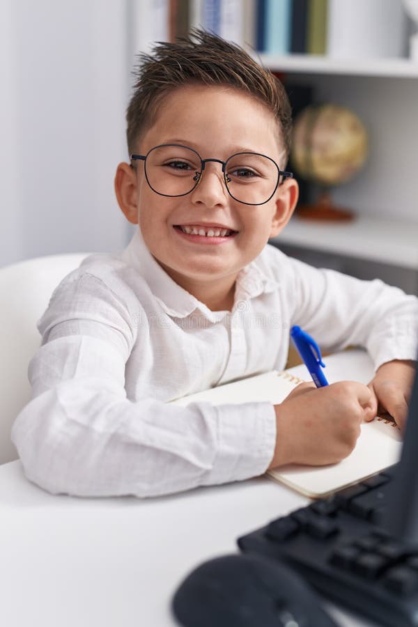 Adorable Hispanic Boy Student Using Computer Writing on Notebook at ...