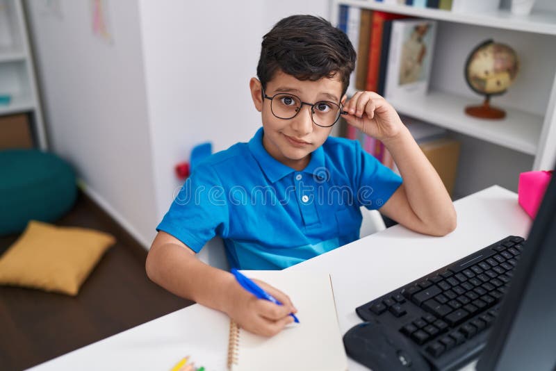 Adorable Hispanic Boy Student Using Computer Writing on Notebook at ...