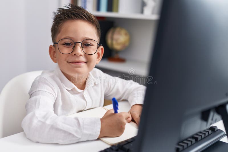 Adorable Hispanic Boy Student Using Computer Writing on Notebook at ...