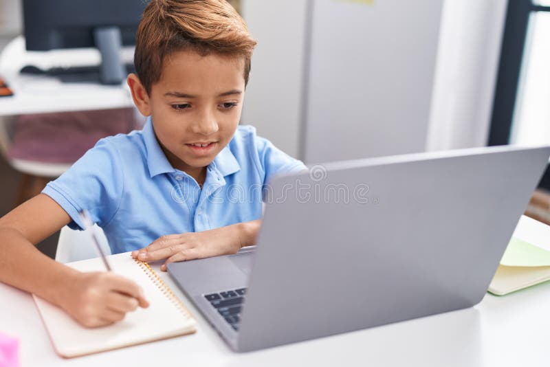 Adorable Hispanic Boy Student Using Computer Writing on Notebook at ...