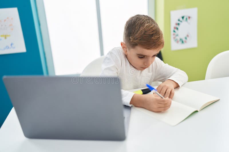 Adorable Hispanic Boy Student Using Laptop Writing Notes at Classroom ...