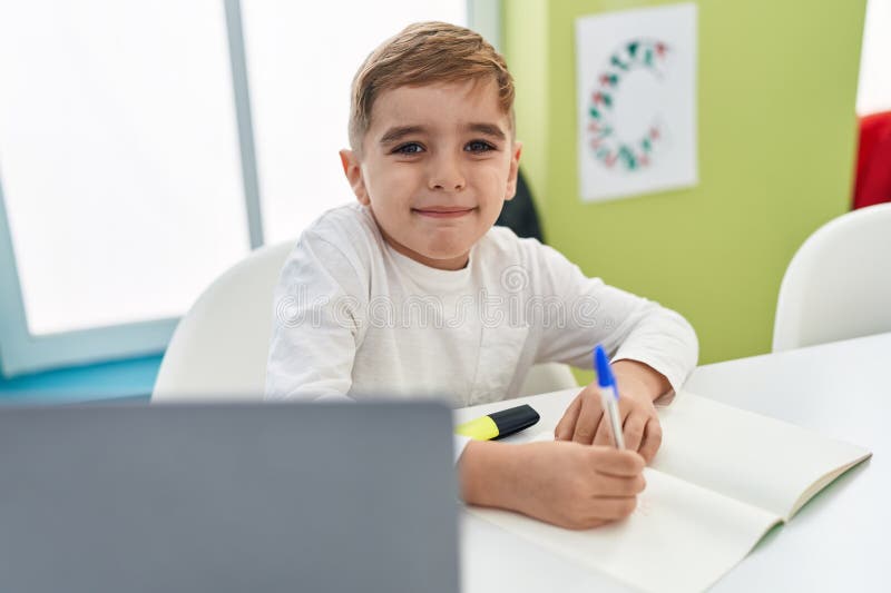 Adorable Hispanic Boy Student Using Laptop Writing Notes at Classroom ...