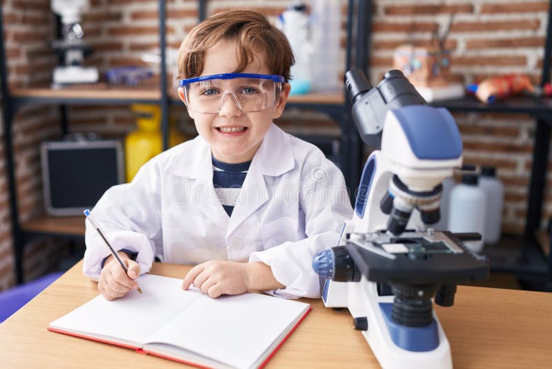 Adorable Hispanic Boy Student Using Microscope Writing on Notebook at ...
