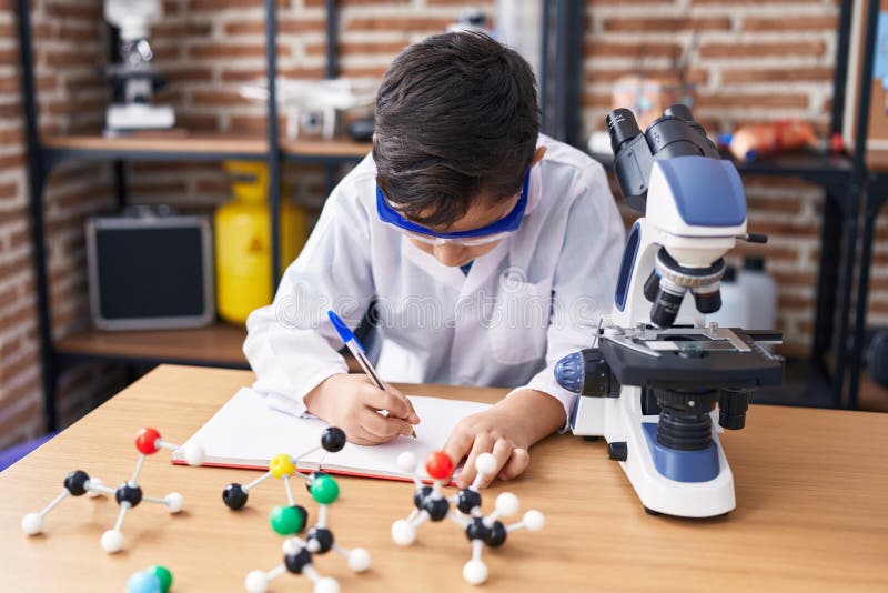 Adorable Hispanic Boy Student Using Microscope Writing on Notebook at ...