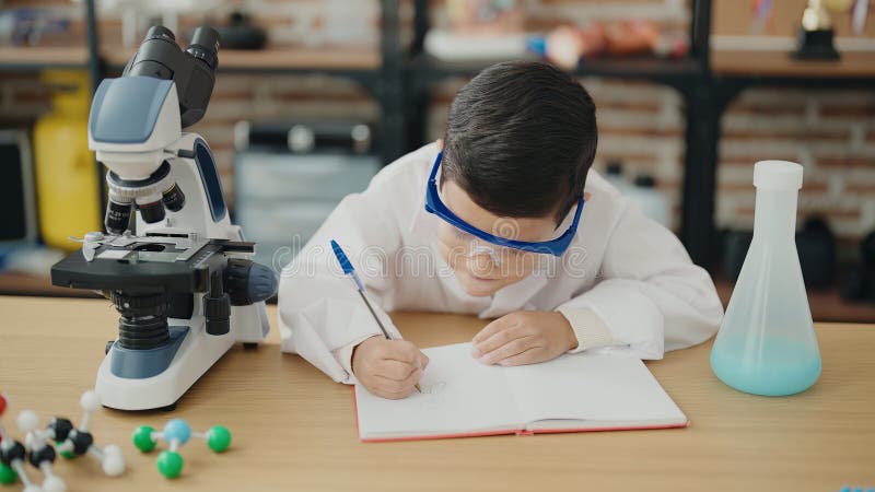 Adorable Hispanic Boy Student Using Microscope Writing on Notebook at ...
