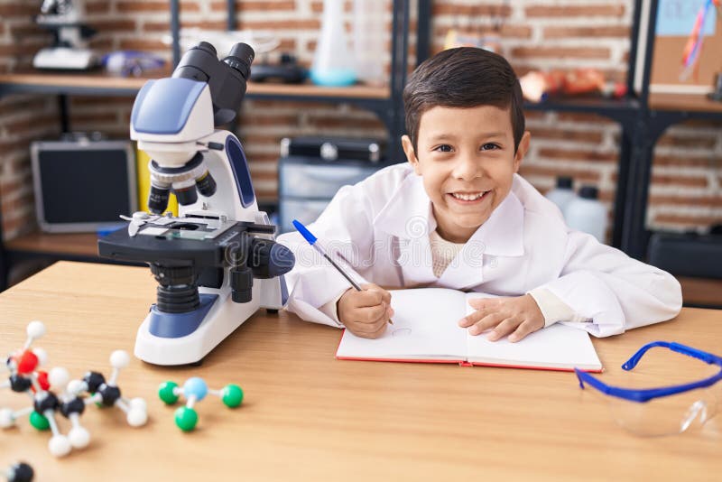 Adorable Hispanic Boy Student Using Microscope Writing on Notebook at ...