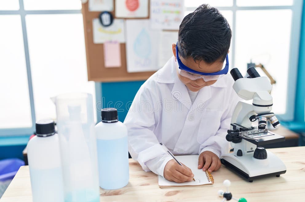 Adorable Hispanic Boy Student Using Microscope Writing Notes at ...