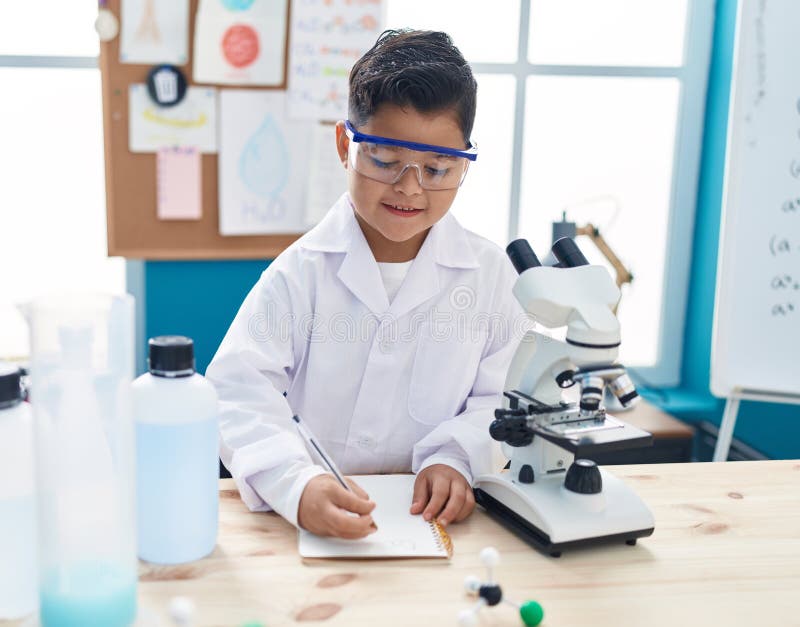 Adorable Hispanic Boy Student Using Microscope Writing Notes at ...
