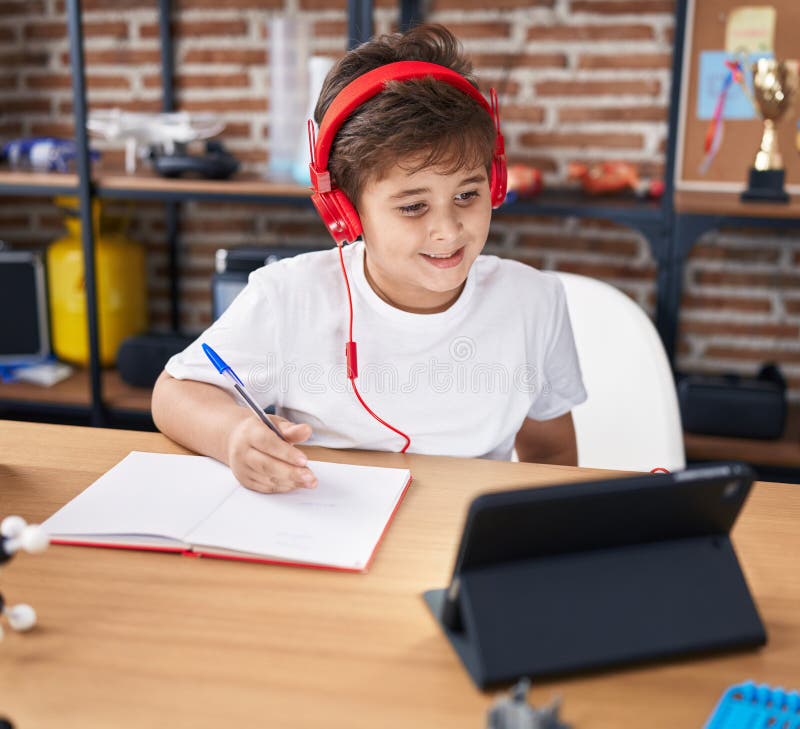 Adorable Hispanic Boy Student Using Touchpad Writing on Notebook at ...