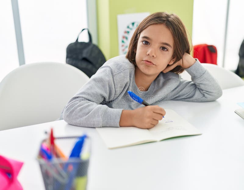 Adorable Hispanic Boy Student Writing on Notebook at Classroom Stock ...