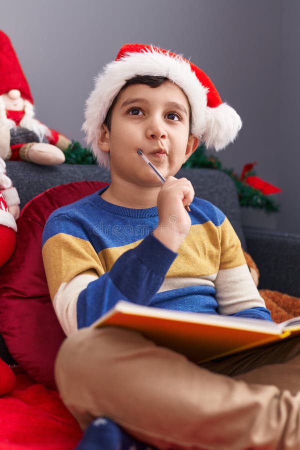 Adorable Hispanic Boy Writing on Notebook Sitting on Sofa by Christmas ...