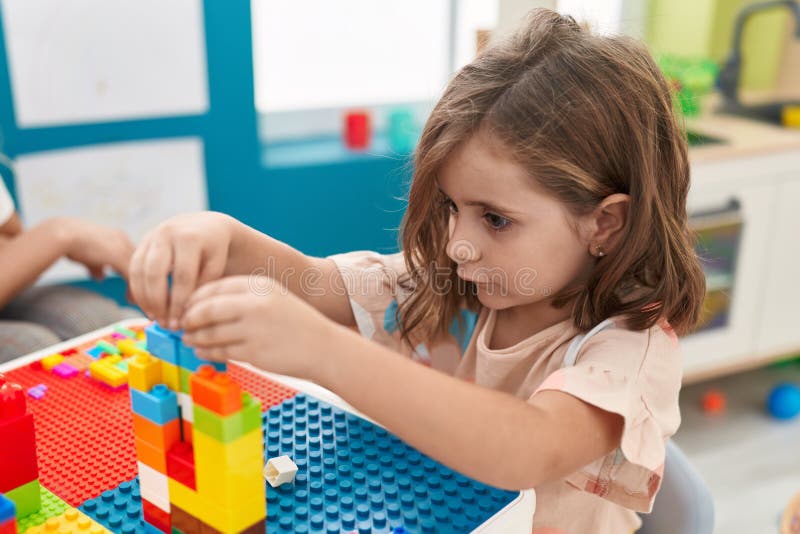 Adorable Hispanic Girl Playing with Construction Blocks Sitting on Table at Kindergarten Stock ...