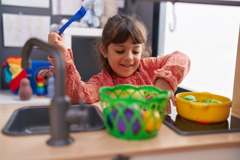 Adorable Hispanic Girl Playing with Play Kitchen Standing at ...