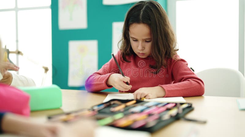 Adorable Hispanic Girl Student Drawing on Notebook at Classroom Stock ...