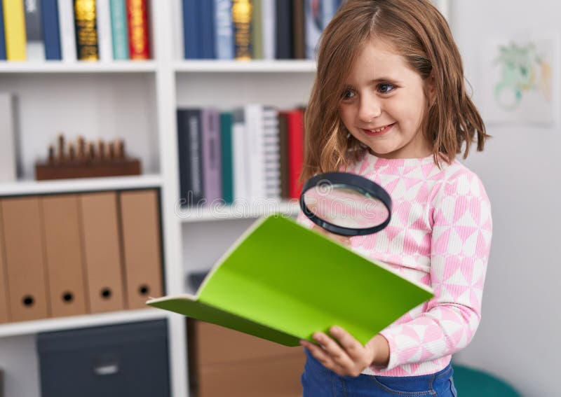 Adorable Hispanic Girl Student Reading Book Using Magnifying Glass at ...