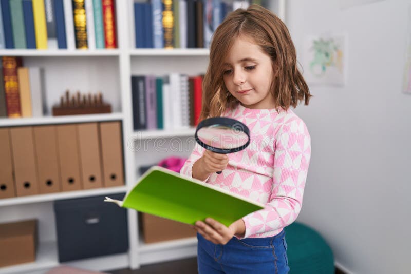 Adorable Hispanic Girl Student Reading Book Using Magnifying Glass at ...