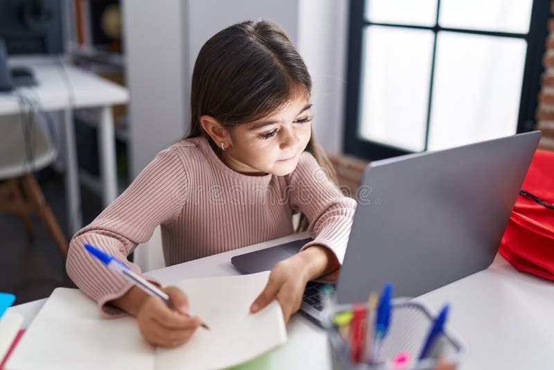 Adorable Hispanic Girl Student Using Laptop Writing on Notebook at ...