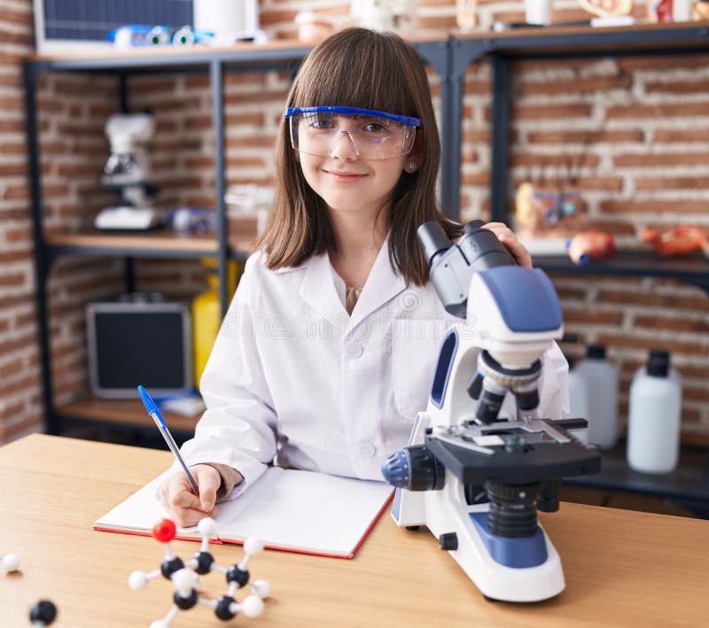 Adorable Hispanic Girl Student Using Microscope Writing on Noteboo at ...