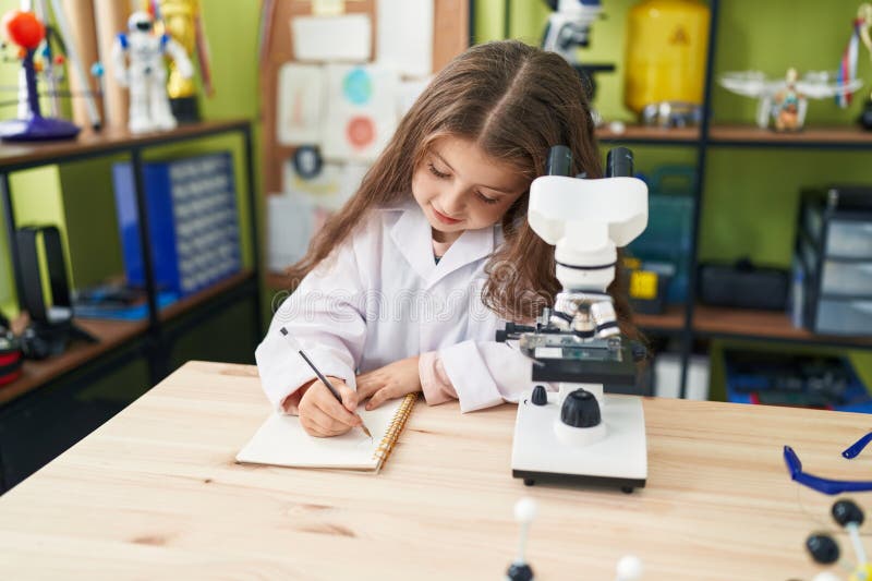 Adorable Hispanic Girl Student Using Microscope Writing Notes at ...