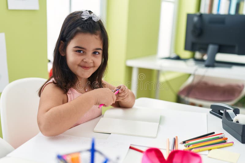 Adorable Hispanic Girl Student Writing on Notebook at Classroom Stock ...