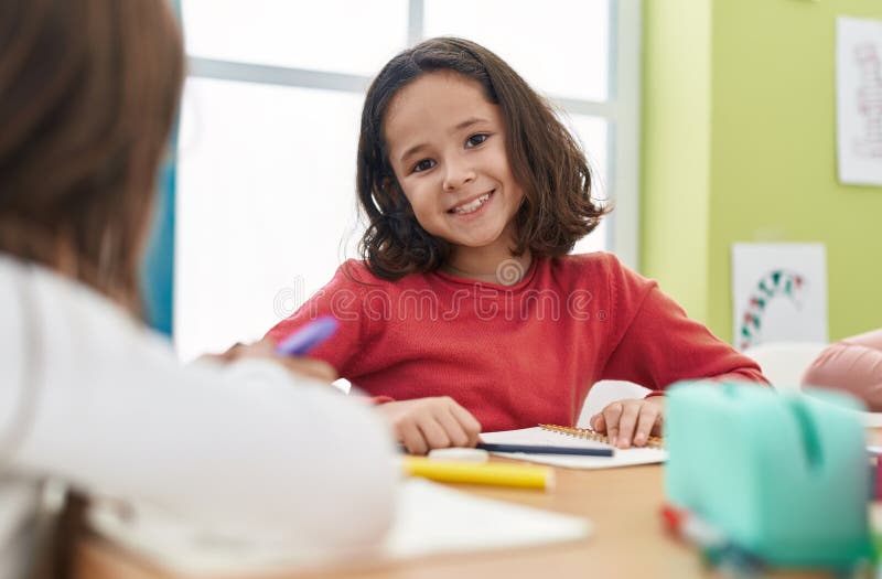 Adorable Hispanic Girl Student Writing on Notebook at Classroom Stock ...