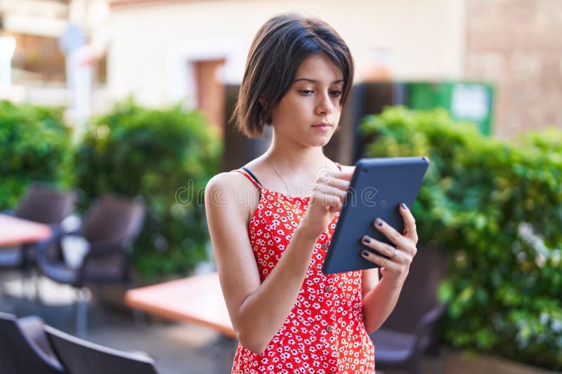 Adorable Hispanic Girl Using Touchpad with Serious Expression at Street ...