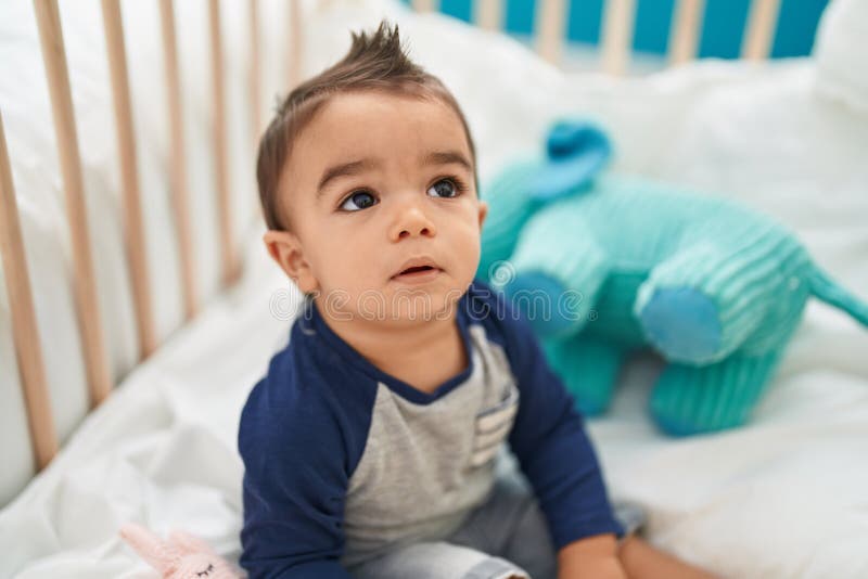 Adorable Hispanic Toddler Sitting on Cradle with Relaxed Expression at ...