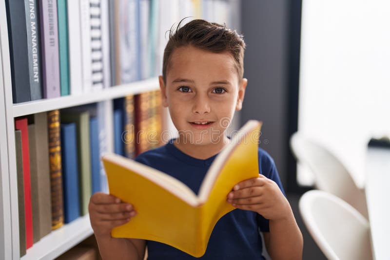 Adorable Hispanic Toddler Student Reading Book Standing at Library ...