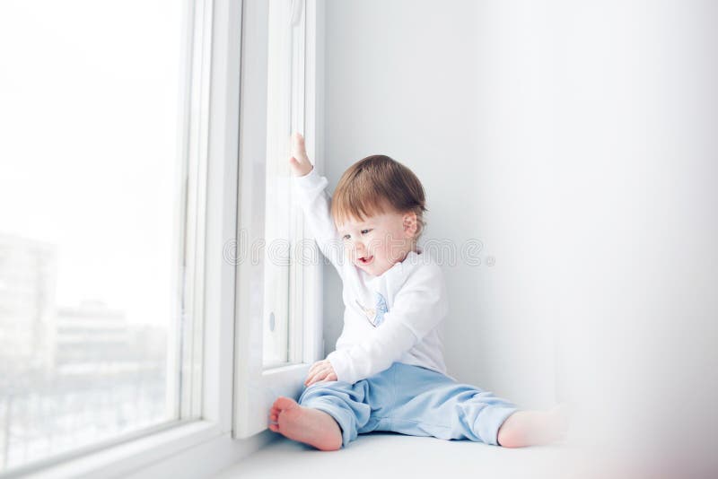 Adorable Little Baby Seating on Windowsill. Looking Out the Window ...