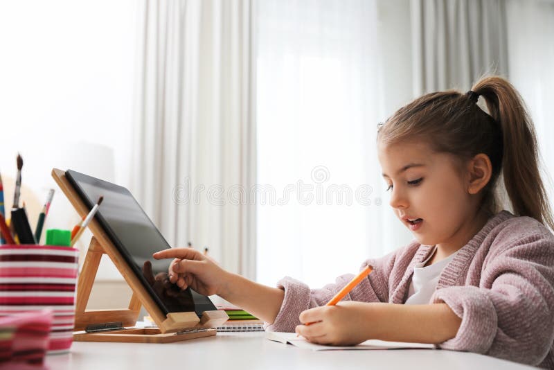 Adorable Little Girl Doing Homework with Tablet at Table Stock Photo ...