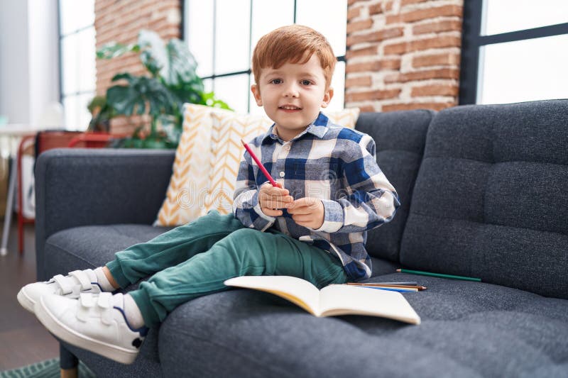 Adorable Toddler Drawing on Notebook Sitting on Sofa at Home Stock ...