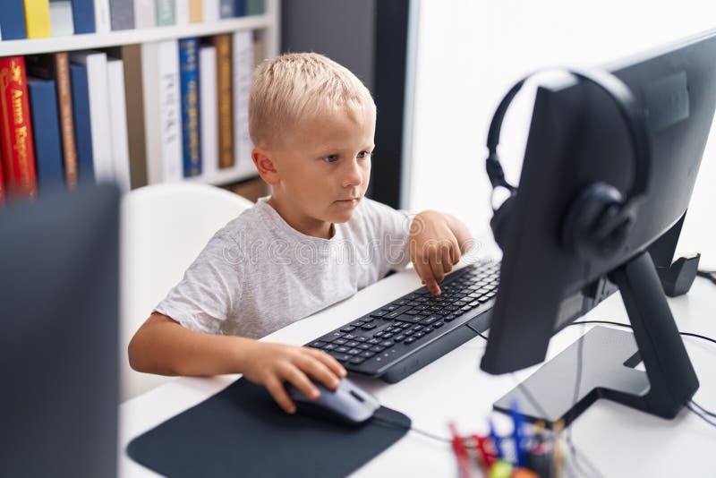 Adorable Toddler Student Using Computer Sitting on Table at Classroom ...