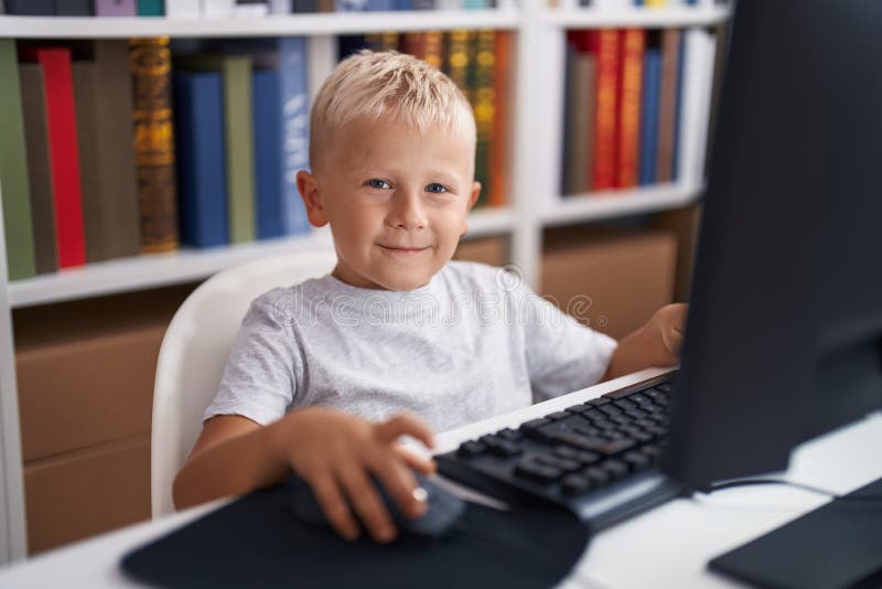 Adorable Toddler Student Using Computer Sitting on Table at Classroom ...