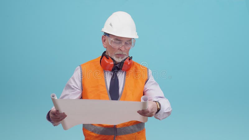 Adult Engineer Man in a Working Protective Uniform, Looks at Schemes of ...