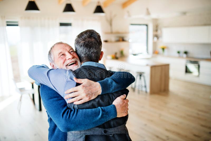 An Adult Hipster Son And Senior Father Indoors At Home Hugging Stock