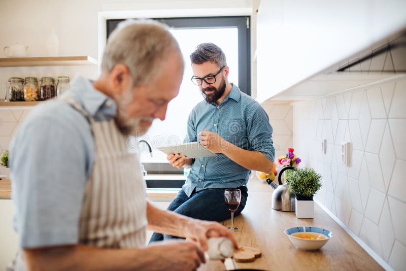 Adult Hipster Son And Senior Father Indoors In Kitchen At Home Using