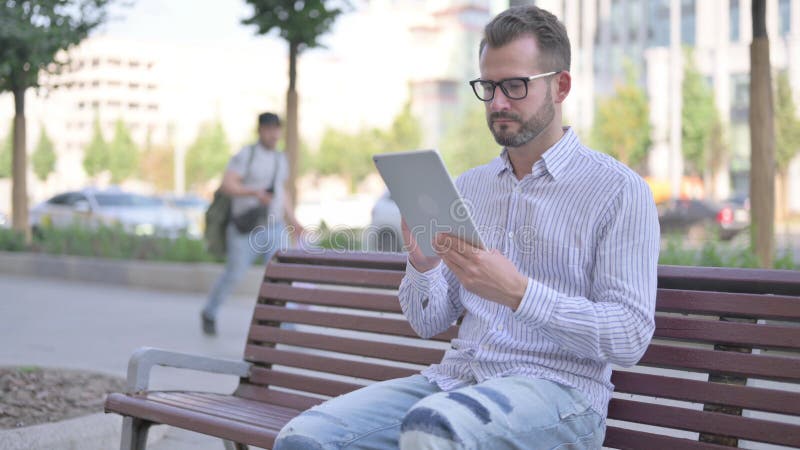 Young Adult Man Using Tablet while Sitting Outdoor on Bench Stock Image ...
